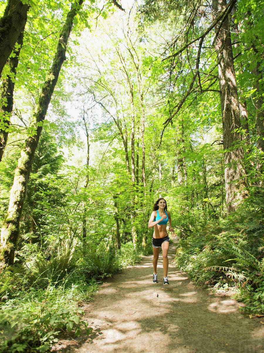 Young woman jogging in forest - Royalty-free Stock Photo | Dissolve
