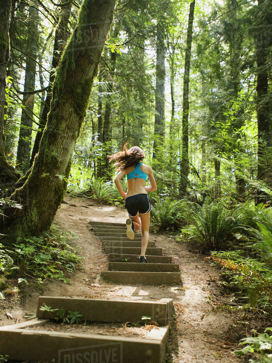 Rear view of young woman jogging in forest - Royalty-free Stock Photo ...