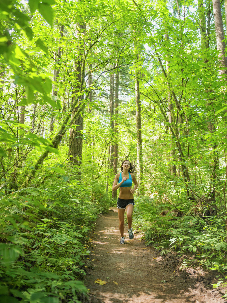 Young woman jogging in forest - Royalty-free Stock Photo | Dissolve
