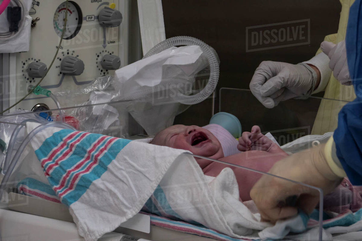 Doctors with crying newborn baby girl (0-1 months) in hospital ...