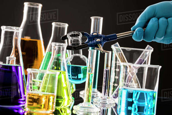 Chemist combining colorful liquids in laboratory glassware - Stock ...