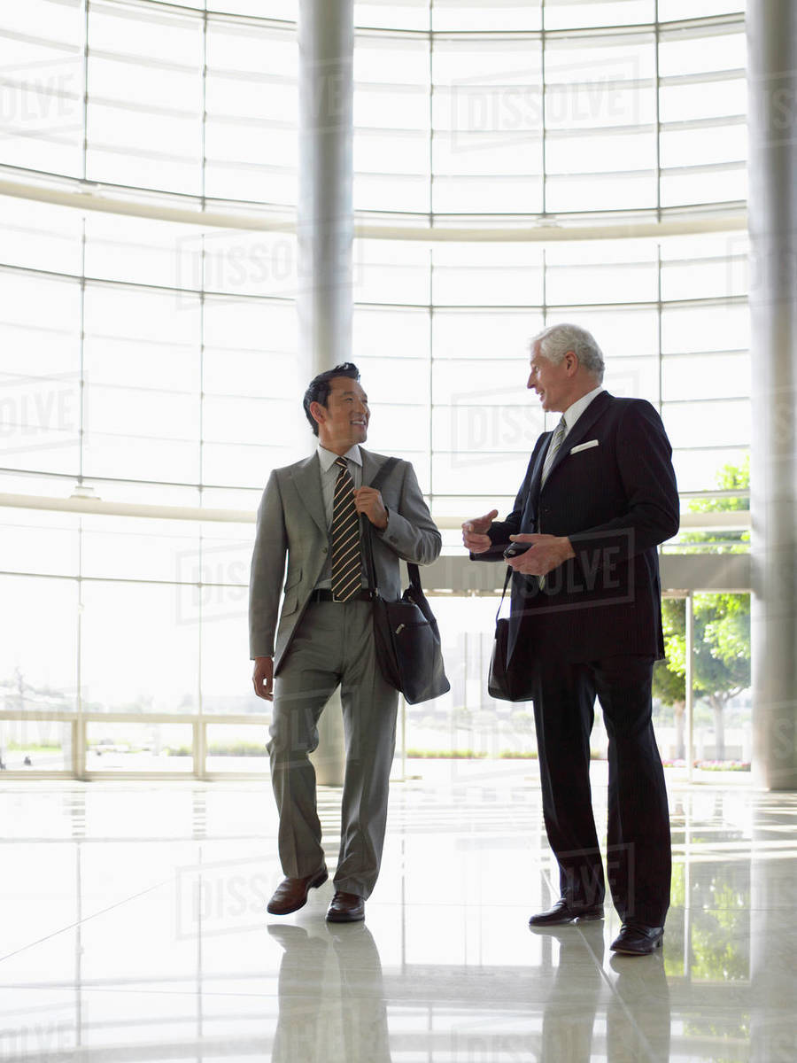 Two businessmen talking in lobby - Stock Photo - Dissolve
