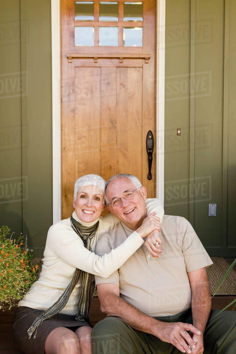 Happy couple embracing in front of house - Stock Photo - Dissolve