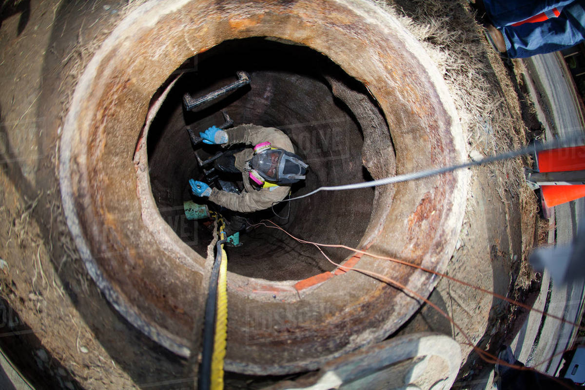 Worker in manhole installing cable - Royalty-free Stock Photo | Dissolve