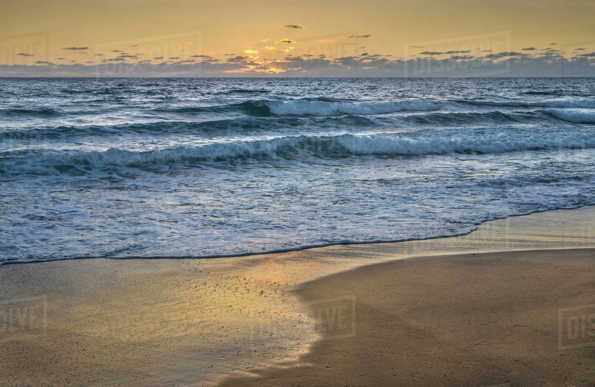 Ocean waves washing beach at sunset - Stock Photo - Dissolve