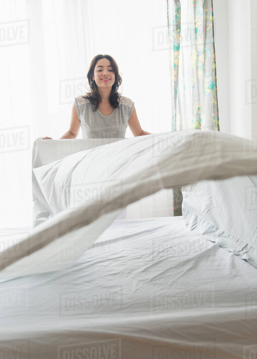 Young woman making bed - Stock Photo - Dissolve