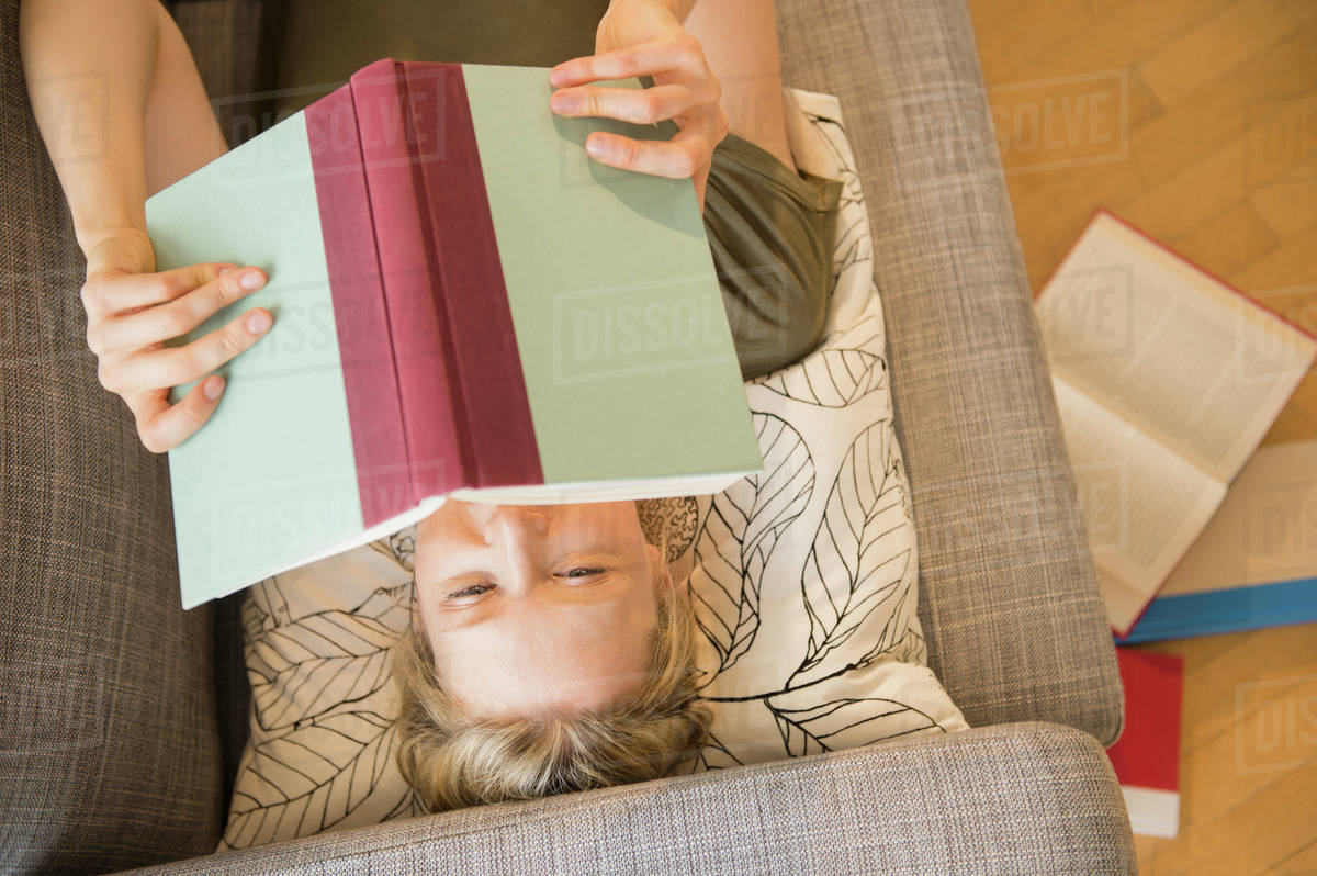 Woman reading book on sofa - Stock Photo - Dissolve