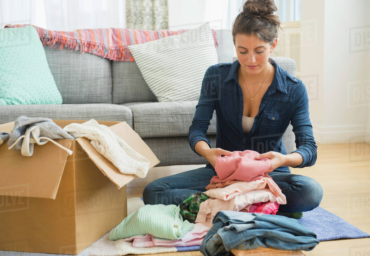 Woman packing clothes to box - Royalty-free Stock Photo | Dissolve
