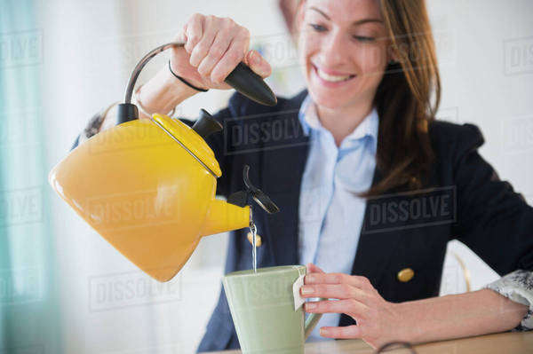 Woman making tea in office - Stock Photo - Dissolve