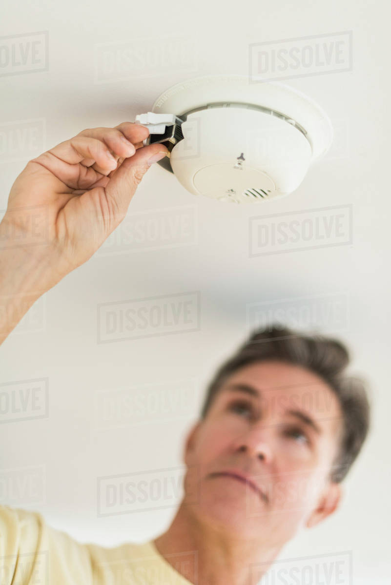 Man changing battery in smoke alarm - Royalty-free Stock Photo | Dissolve
