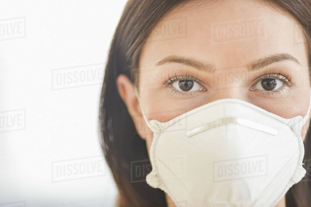 Studio portrait of woman wearing flu mask - Stock Photo - Dissolve