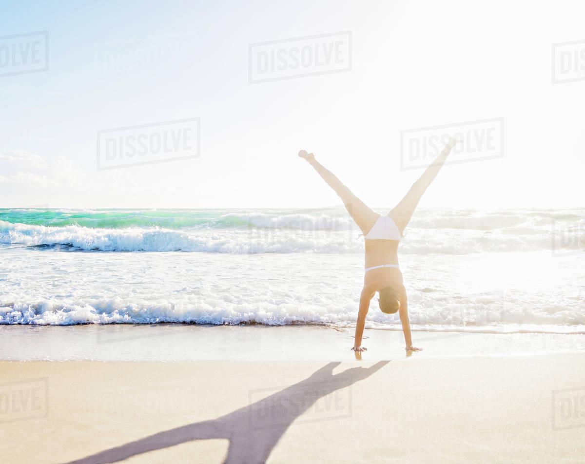 Woman doing handstand on beach - Royalty-free Stock Photo | Dissolve