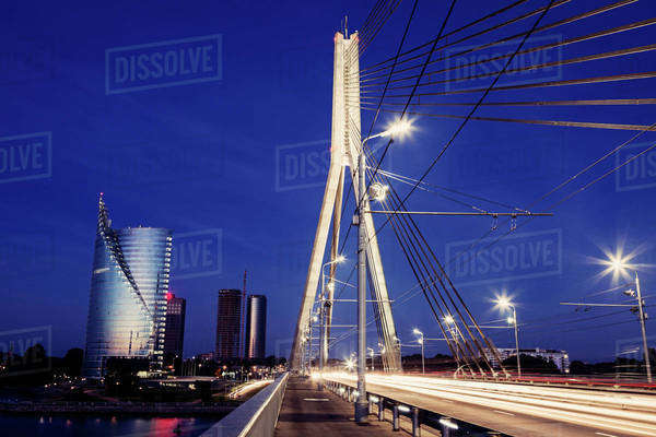 Suspension bridge with skyscrapers on background at night - Stock Photo ...