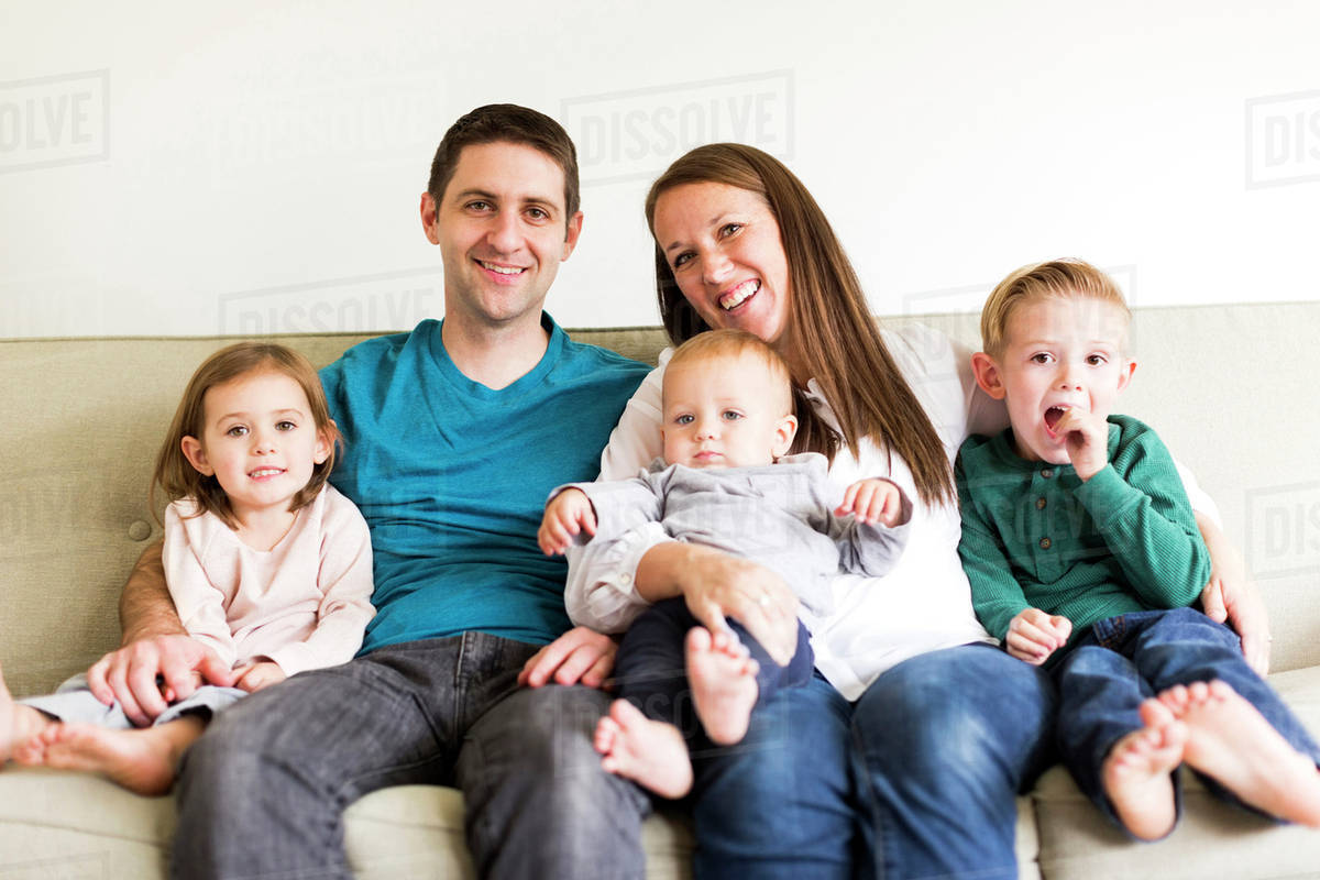 Portrait of family with three children (2-3, 4-5) sitting on sofa ...