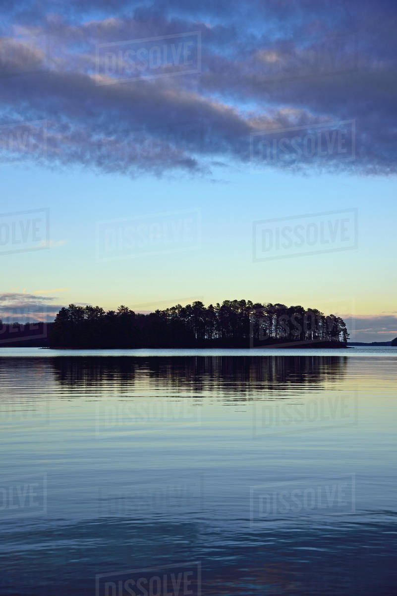 Symmetrical view of trees reflecting in lake at dusk - Royalty-free ...