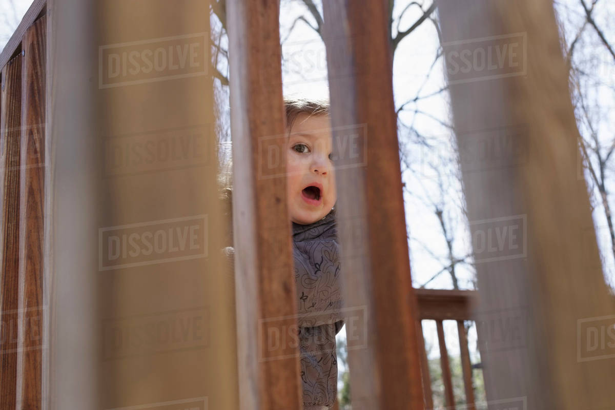 Portrait of girl hiding behind fence - Royalty-free Stock Photo | Dissolve