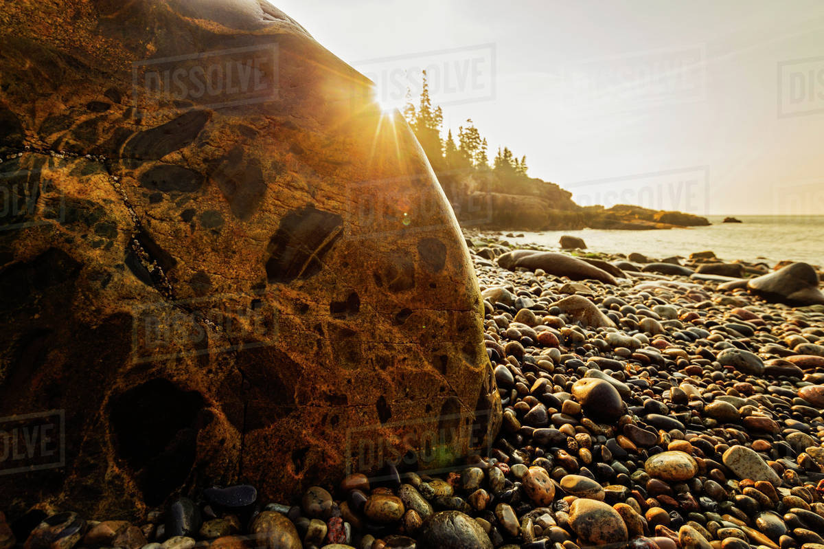 Rocks and pebbles on beach at sunrise - Royalty-free Stock Photo | Dissolve