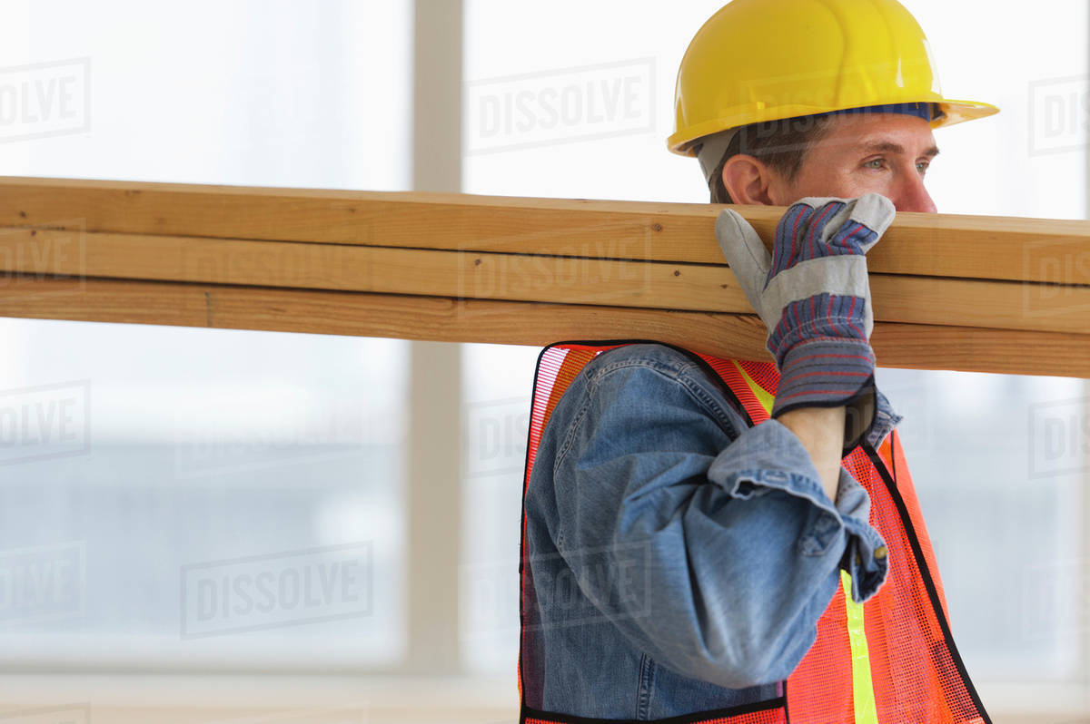 Construction worker carrying planks - Royalty-free Stock Photo | Dissolve