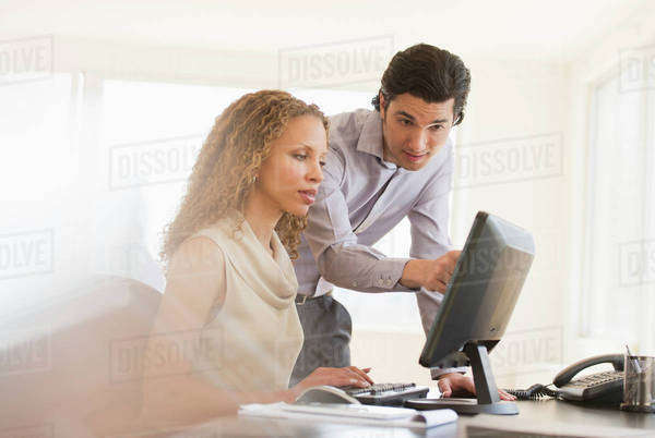 Business man and woman looking at computer - Stock Photo - Dissolve
