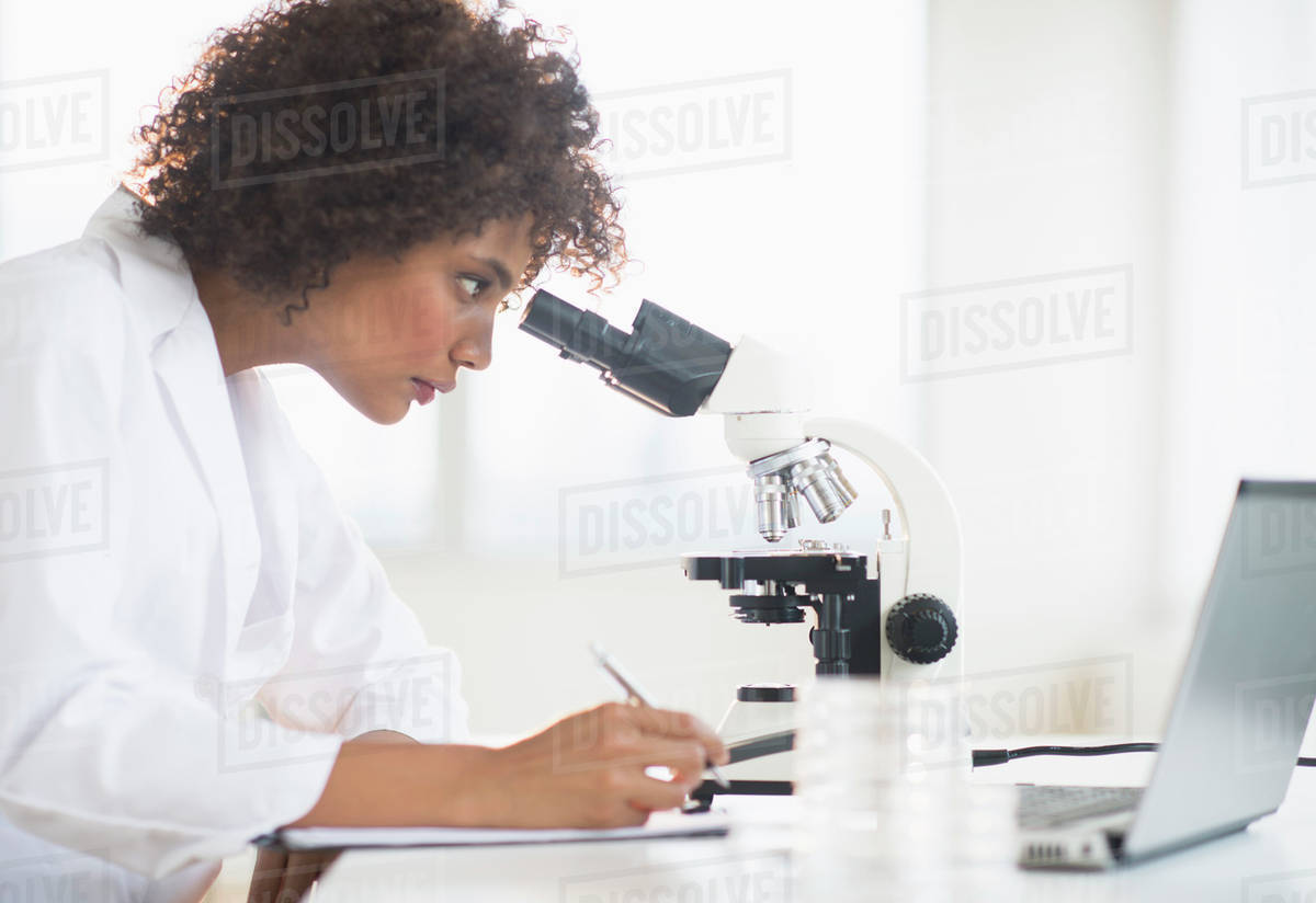 Woman using microscope in laboratory - Royalty-free Stock Photo | Dissolve
