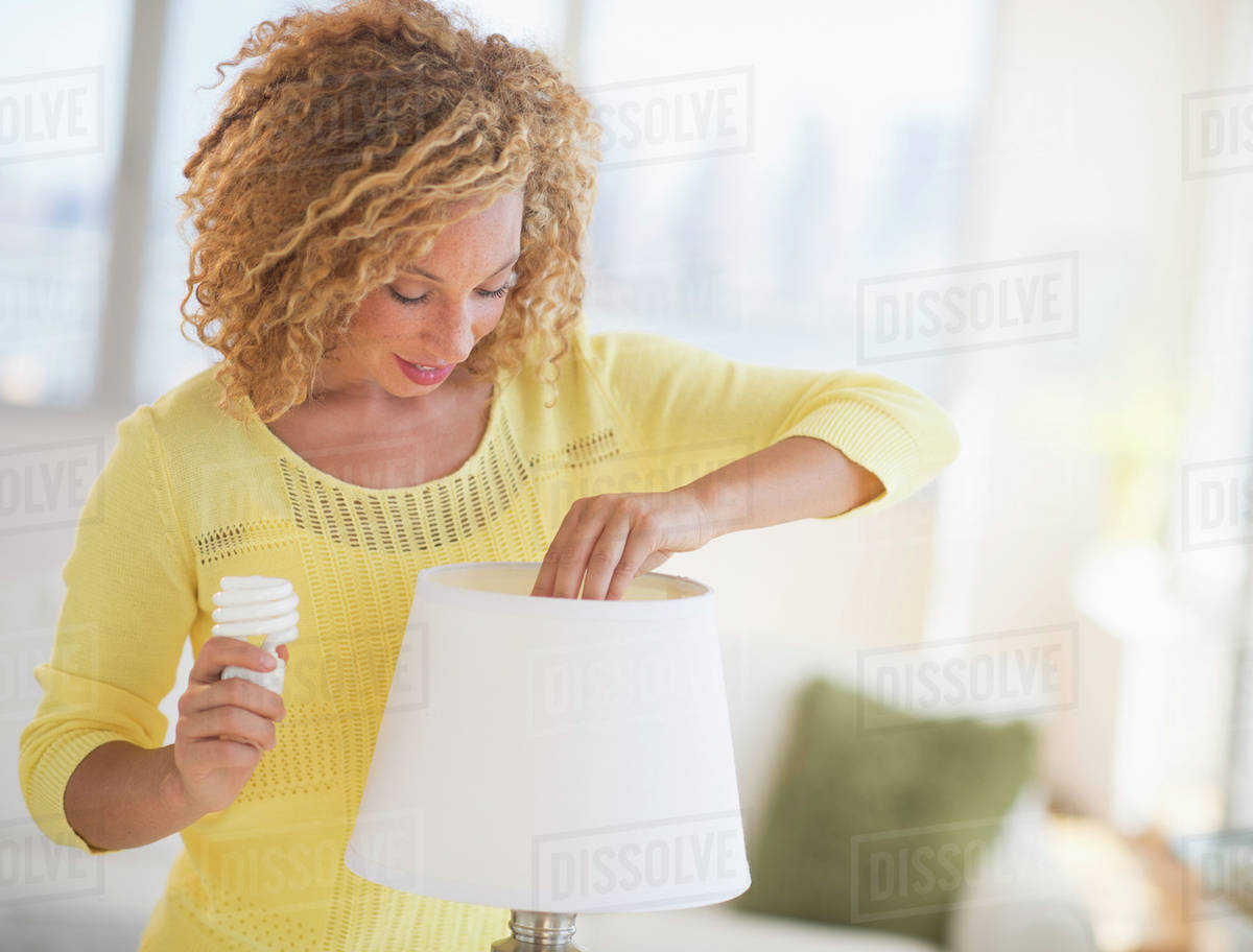 Young woman changing bulb in lamp - Royalty-free Stock Photo | Dissolve