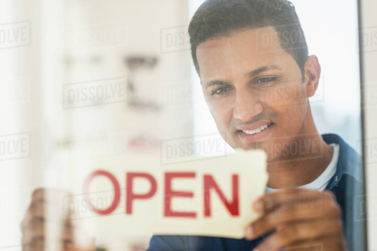 Man placing open sign on door - Royalty-free Stock Photo | Dissolve