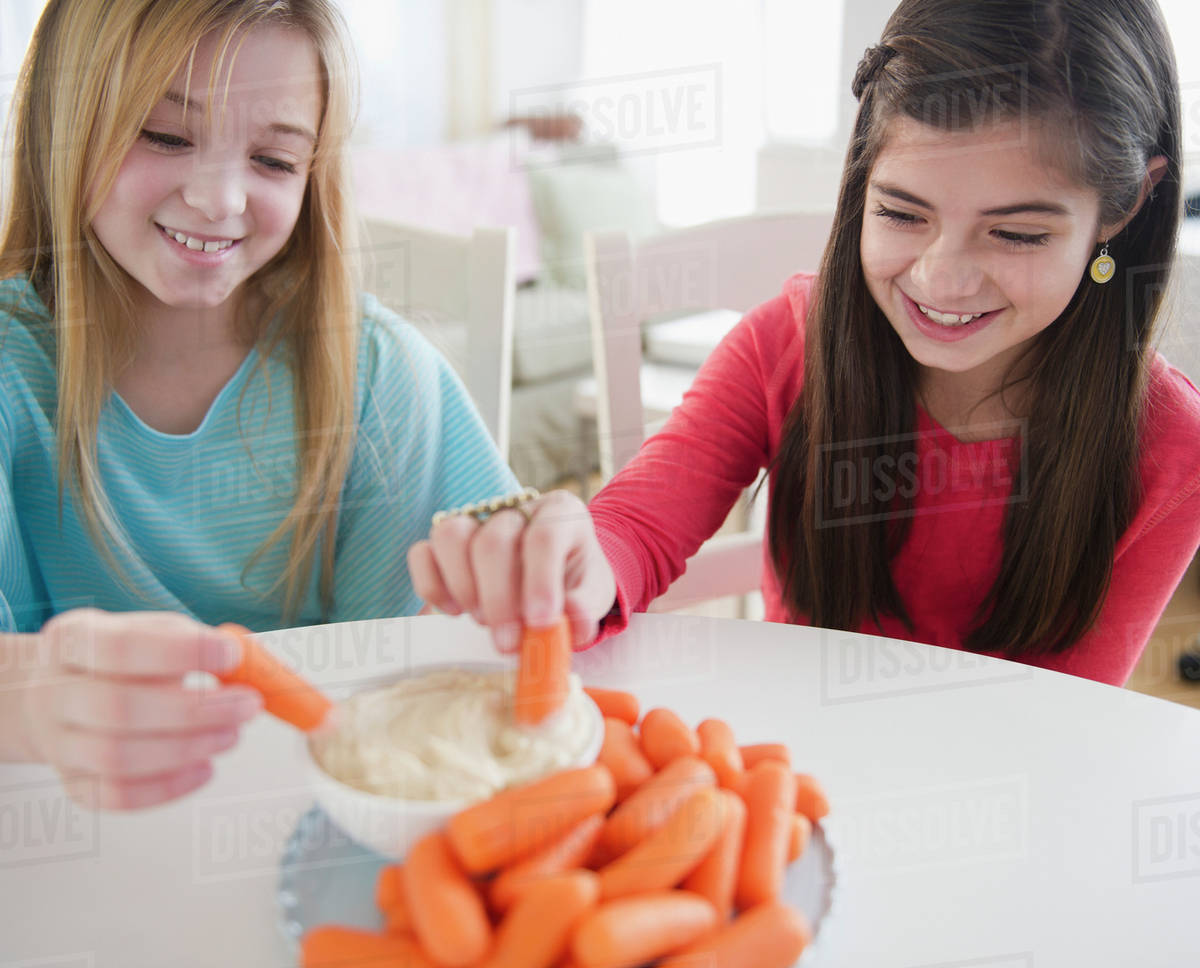 Two girls eating carrots - Stock Photo - Dissolve