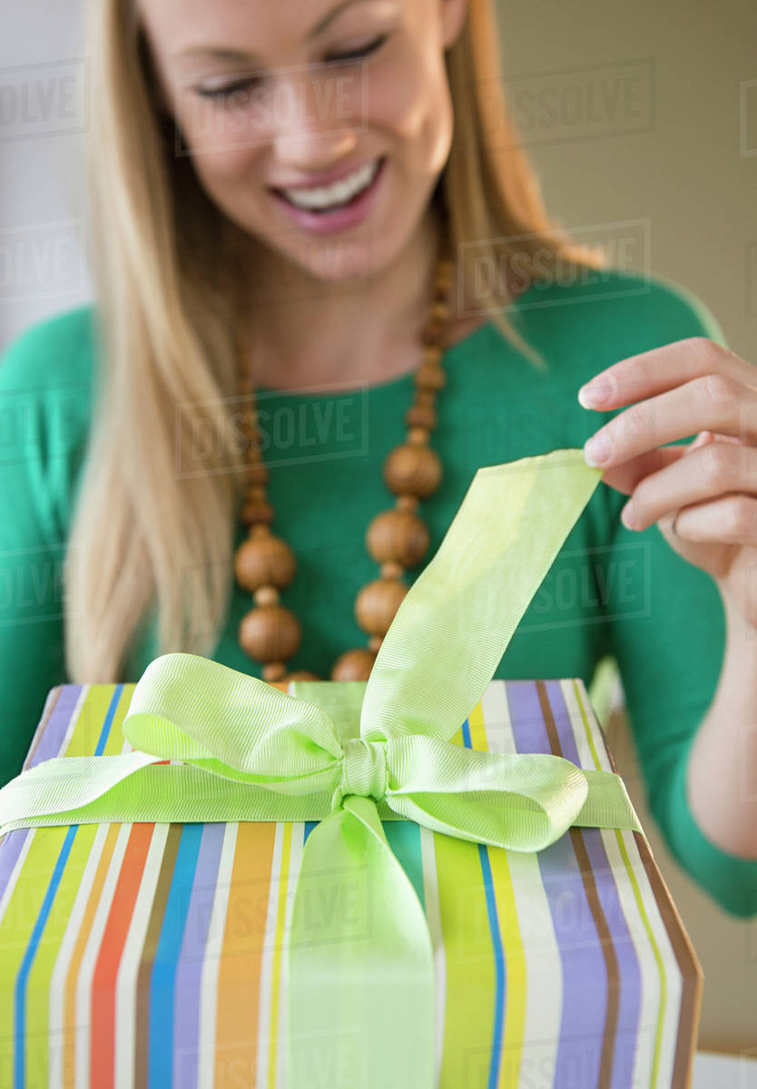 Smiling young woman opening birthday present - Royalty-free Stock Photo ...