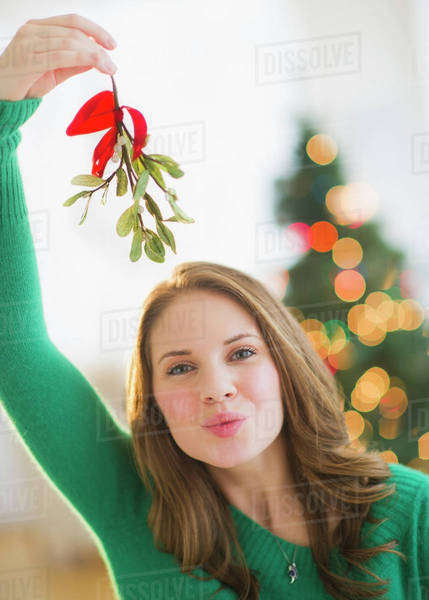Portrait of young woman holding mistletoe stem over head - Royalty-free ...