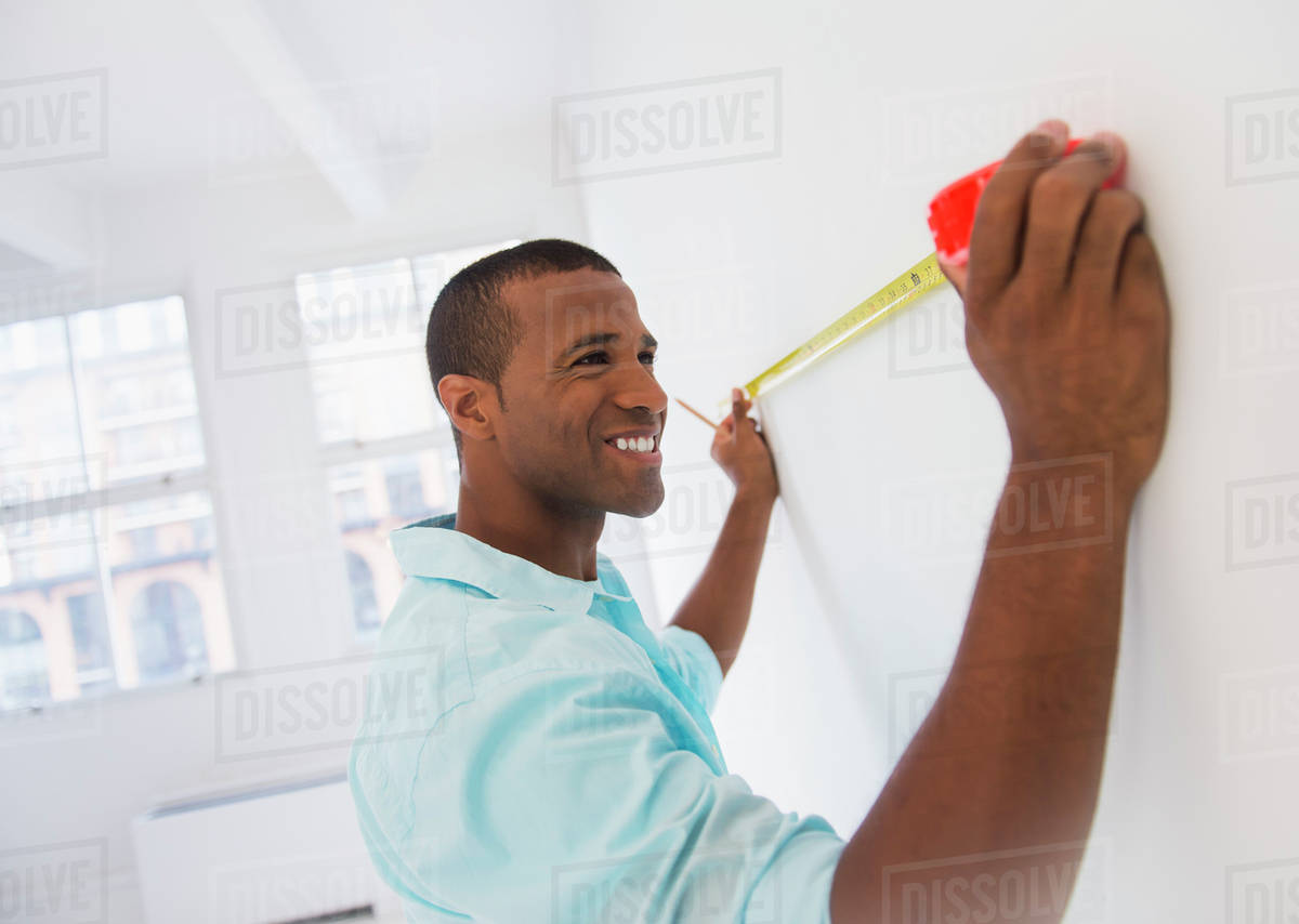 Young man measuring wall in empty room - Royalty-free Stock Photo ...