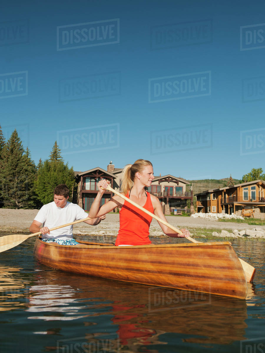 Portrait of two young people paddling canoe - Stock Photo - Dissolve