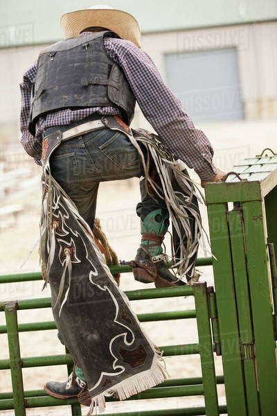Rodeo cowboy climbing on fence - Royalty-free Stock Photo | Dissolve