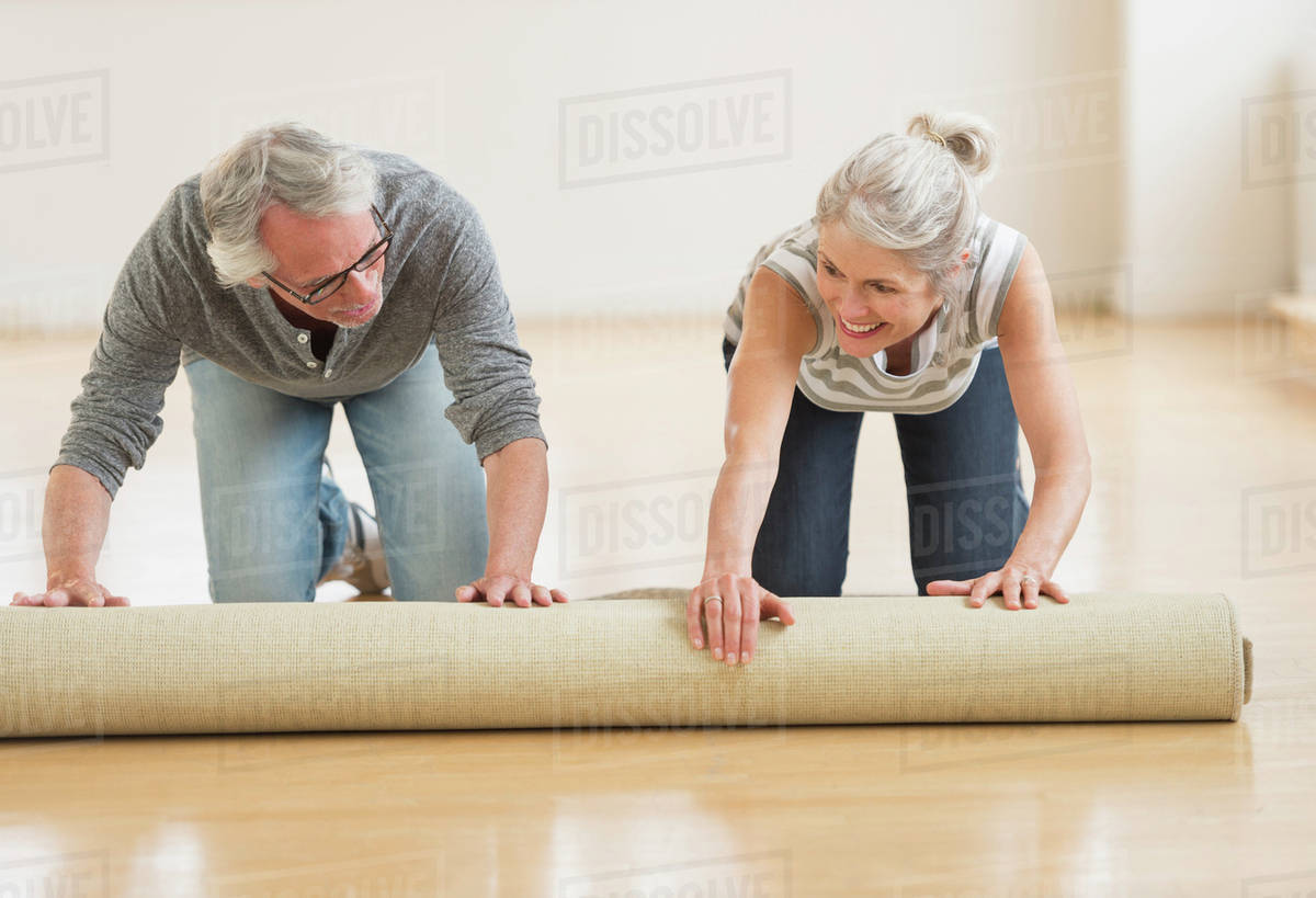 Man and woman rolling carpet - Royalty-free Stock Photo | Dissolve