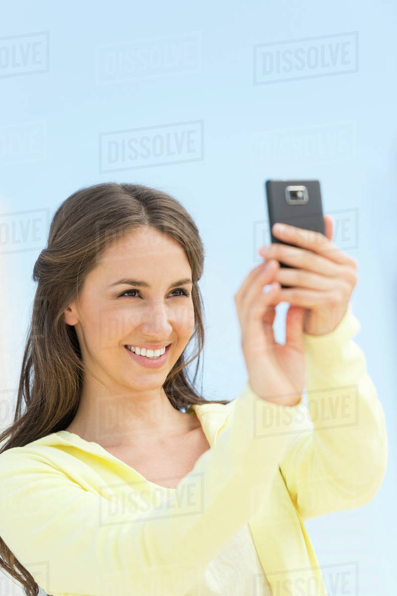 Young woman photographing herself with mobile phone - Royalty-free ...