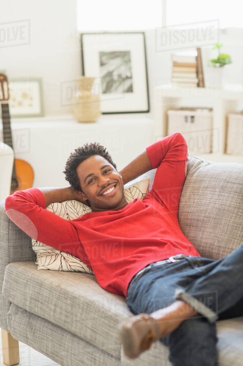 Man lying on sofa and smiling - Royalty-free Stock Photo | Dissolve