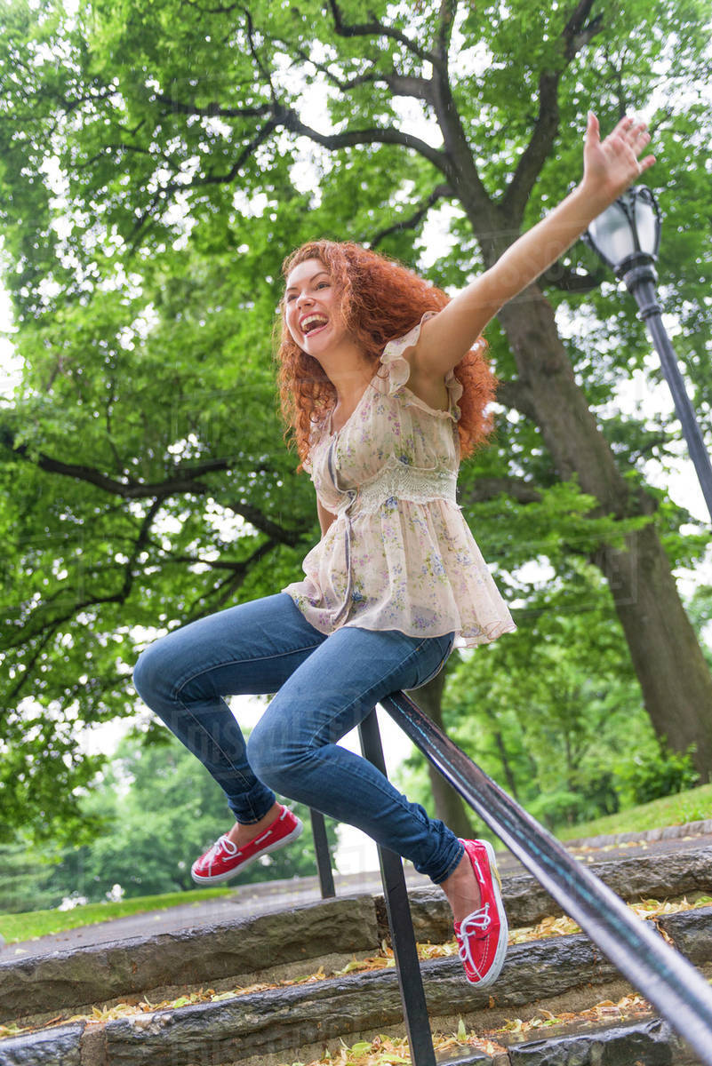 Woman sliding on railing in park - Stock Photo - Dissolve