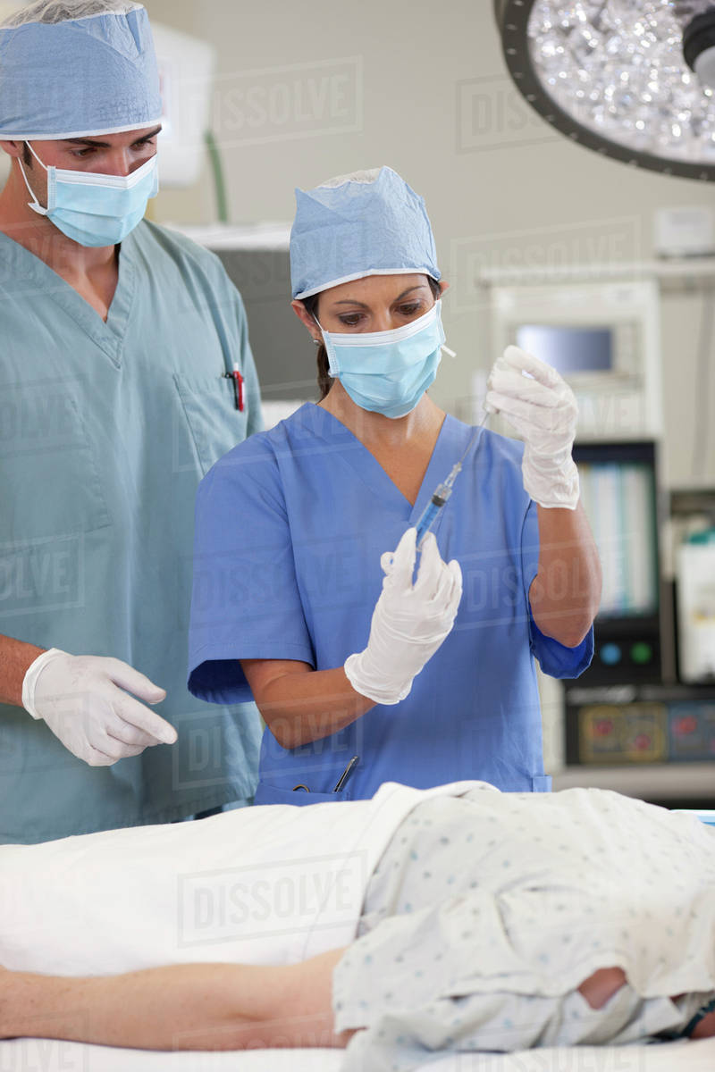 Surgeons preparing patient for surgery - Stock Photo - Dissolve