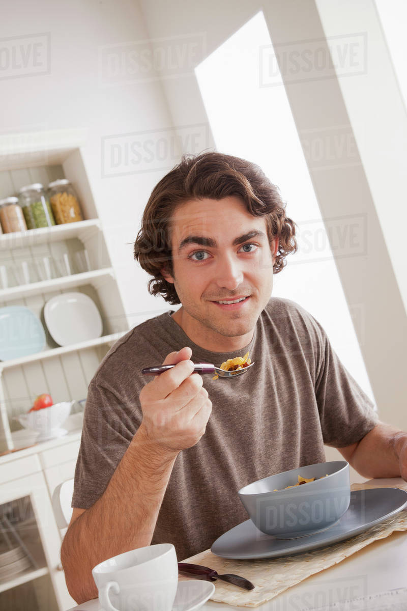 Portrait of young man eating breakfast - Stock Photo - Dissolve