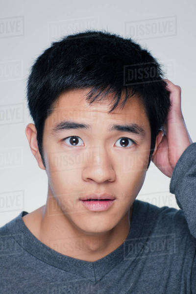 Studio portrait of young man scratching head - Royalty-free Stock Photo ...