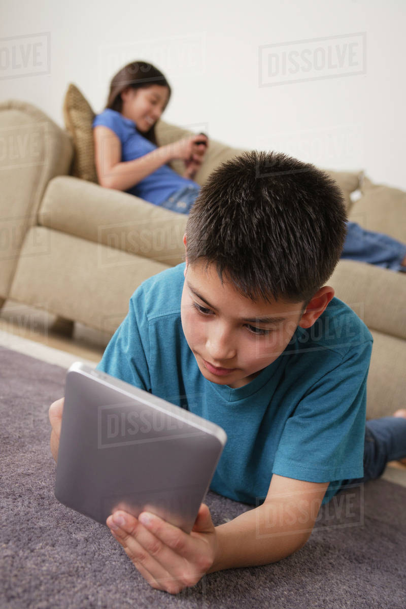 Boy using iPad lying on floor - Stock Photo - Dissolve