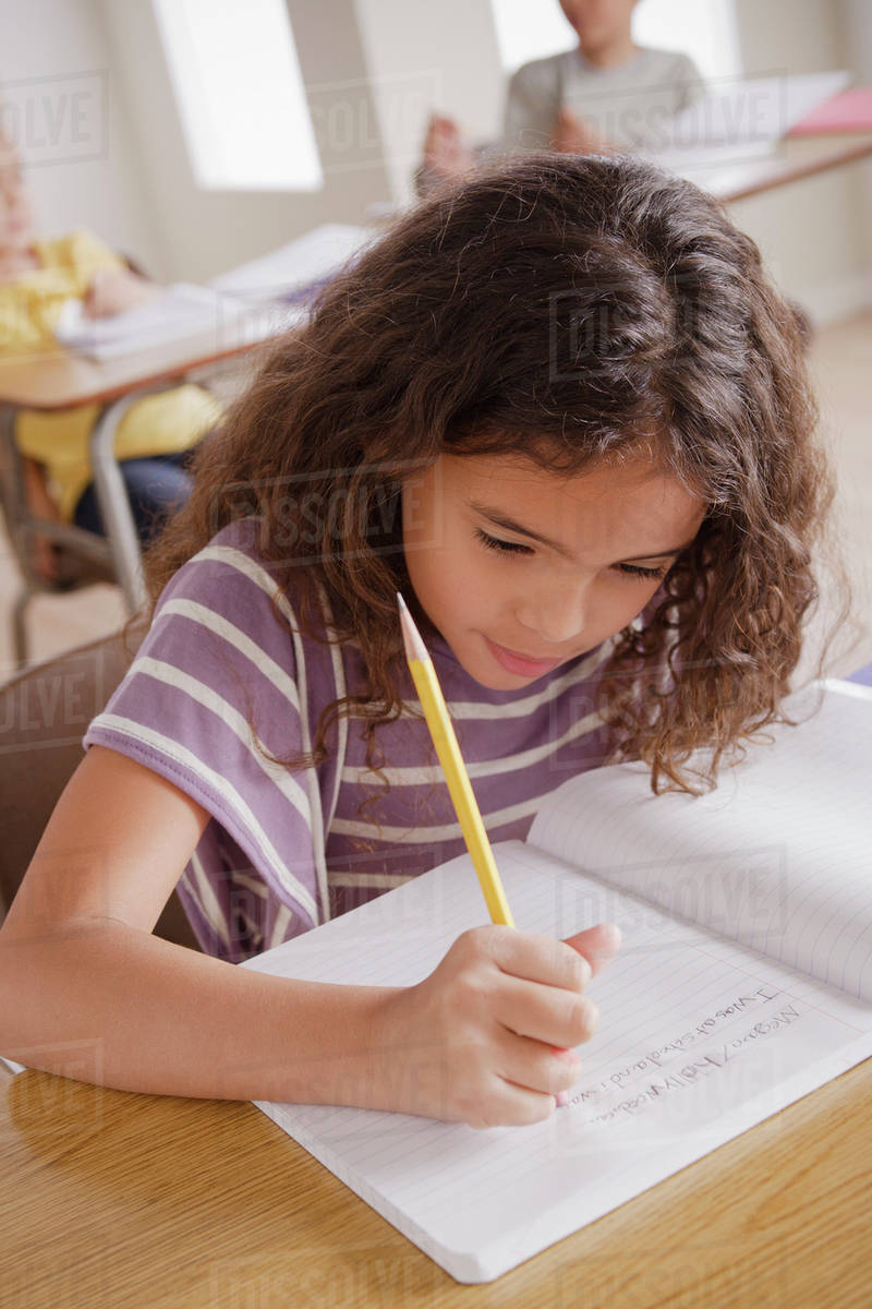 Schoolgirl focused on writing in classroom - Royalty-free Stock Photo ...