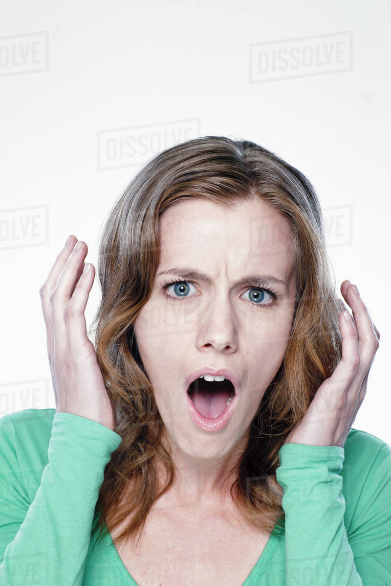 Portrait of shocked young woman, studio shot - Stock Photo - Dissolve