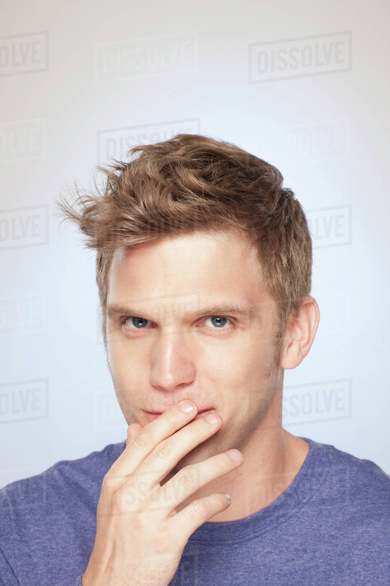 Portrait of man covering his mouth with hand - Stock Photo - Dissolve