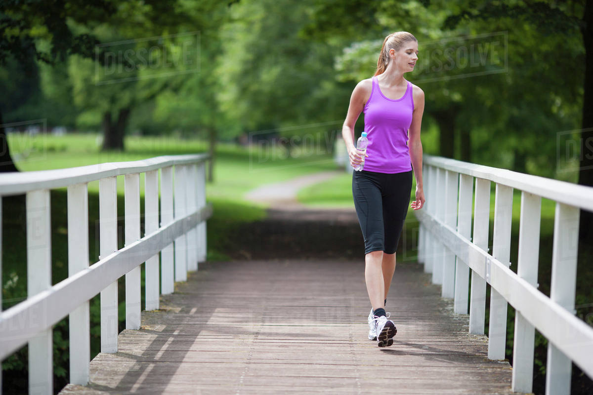 Young woman walking over bridge and looking over edge - Stock Photo ...