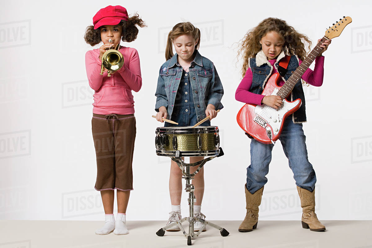Three girls (8-9) playing instruments together, studio shot - Royalty ...