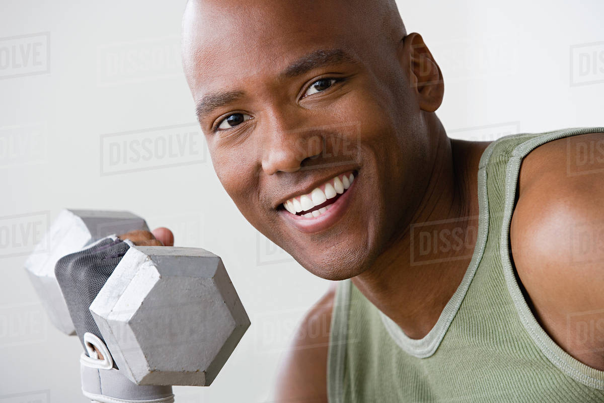 Portrait of smiling young man lifting dumbbell - Royalty-free Stock ...