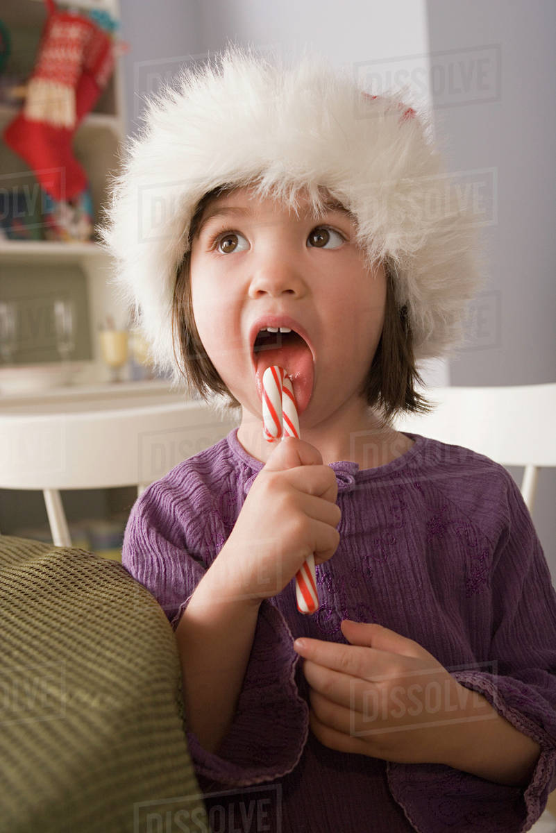 Close-up of girl licking candy cane - Stock Photo - Dissolve
