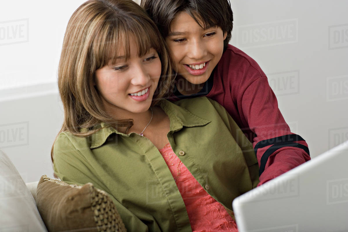 Brother and sister using laptop in living room - Royalty-free Stock ...