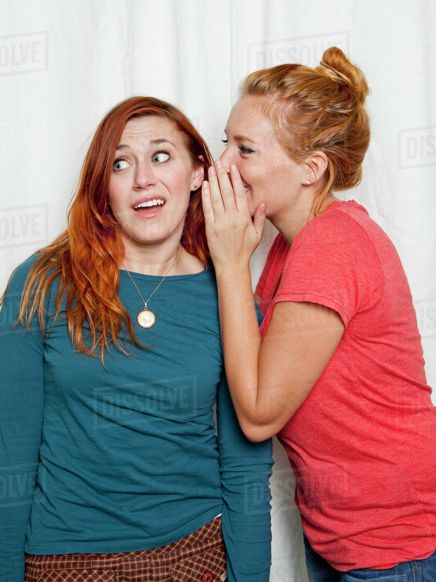 Studio Shot, Young women whispering in friend's ear - Stock Photo ...