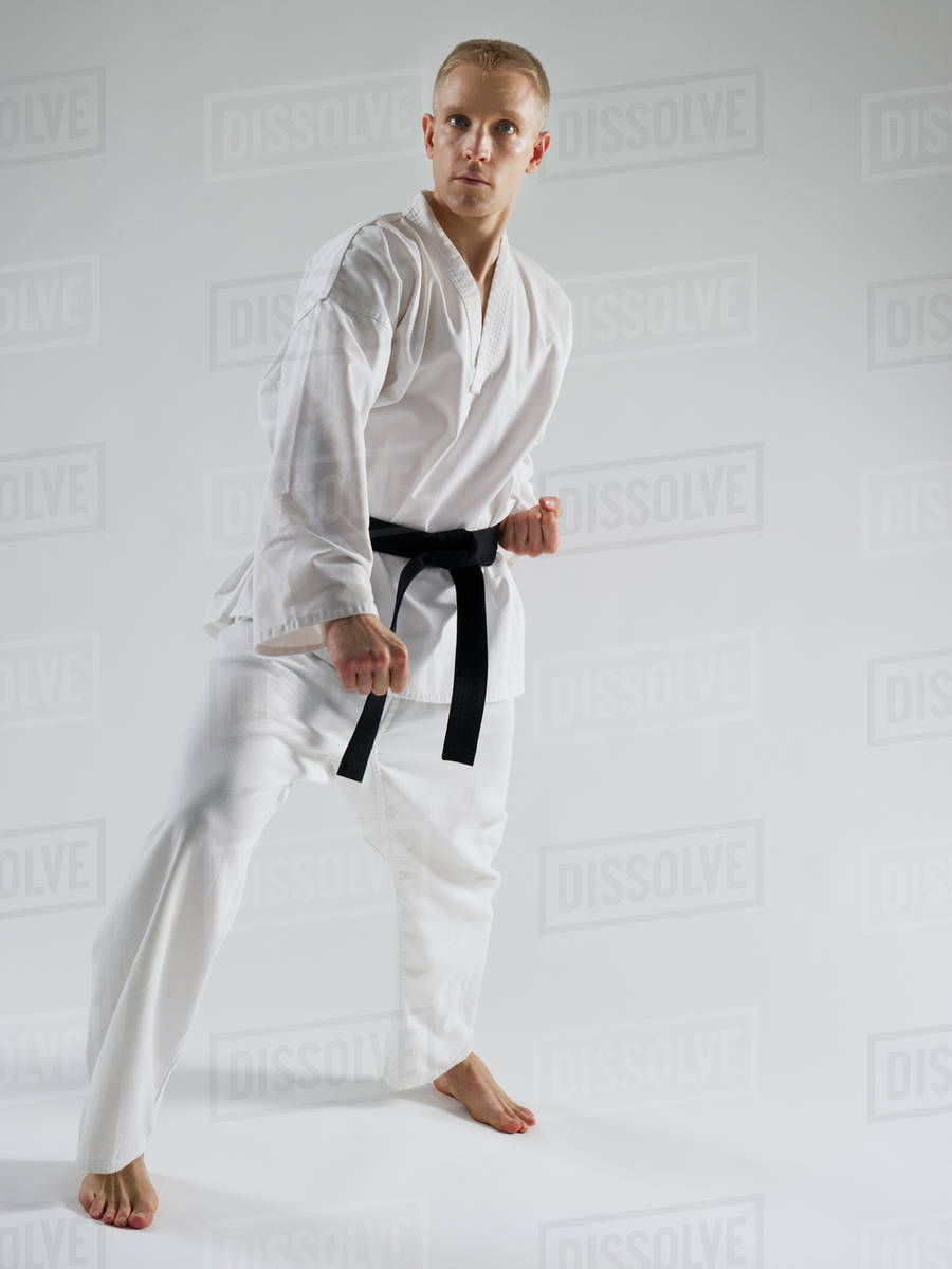 Young man performing karate stance on white background - Royalty-free ...